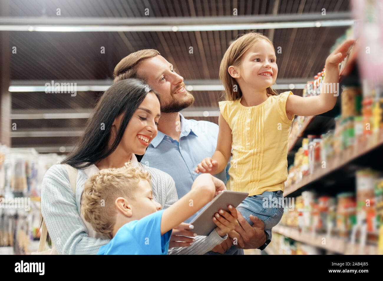 Parents with kids shopping in supermarket, using tablet computer Stock ...