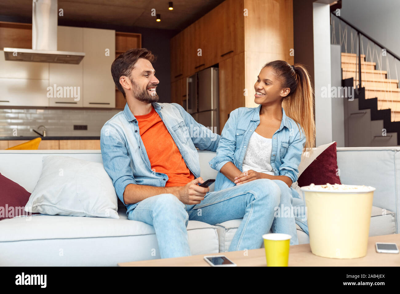 Mixed Race Marriage. Young man and woman watching tv together looking ...