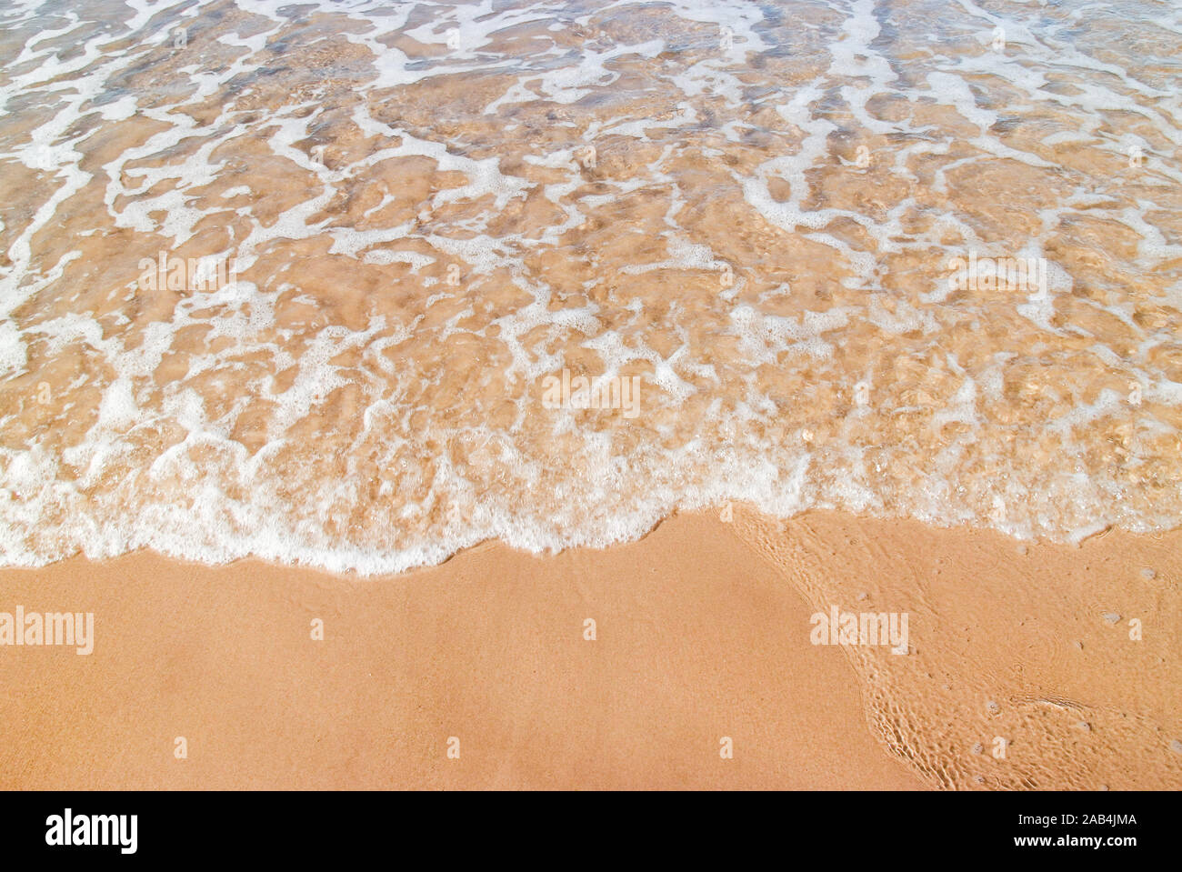 Shallow water on the shore as gentle waves break over warm yellow sand ...