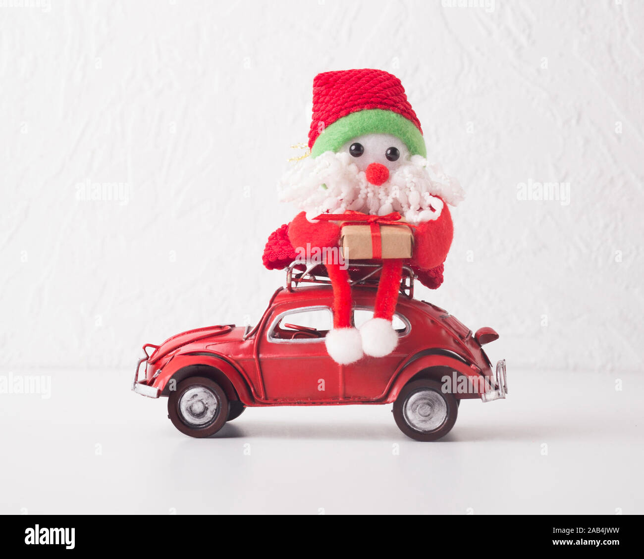 Toy Santa with presents driving on car Volkswagen Beetle on white ...