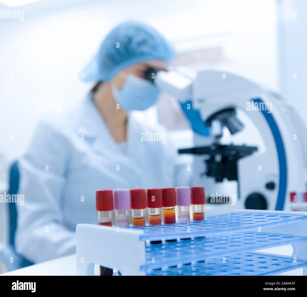 Blurred woman looking in microscope for making blood test Stock Photo ...