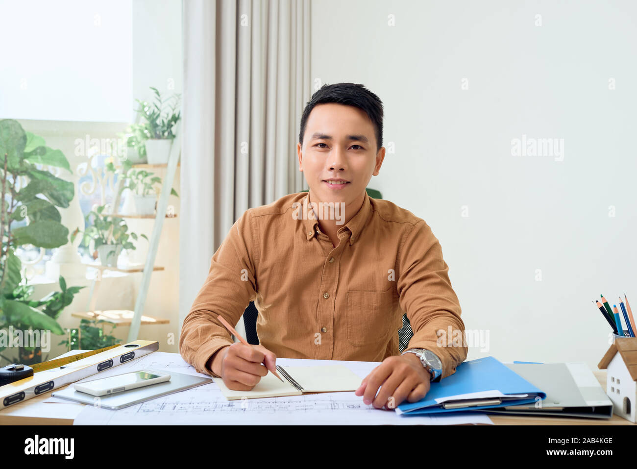 Portrait of young Asian architect man woking with blueprint at his ...