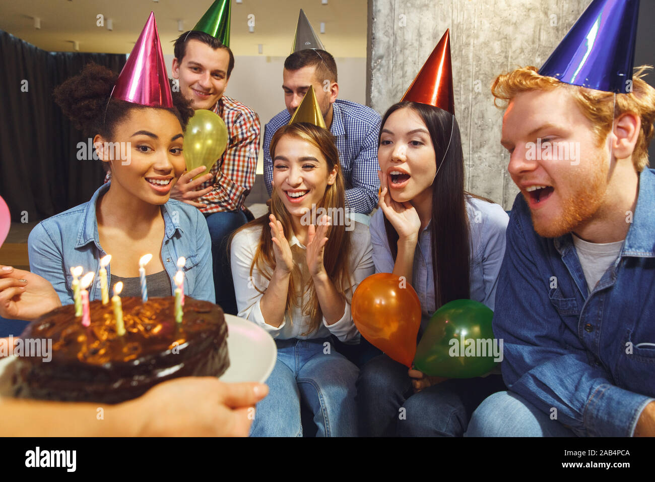 Group of friends having party indoors fun together guy bringing cake ...