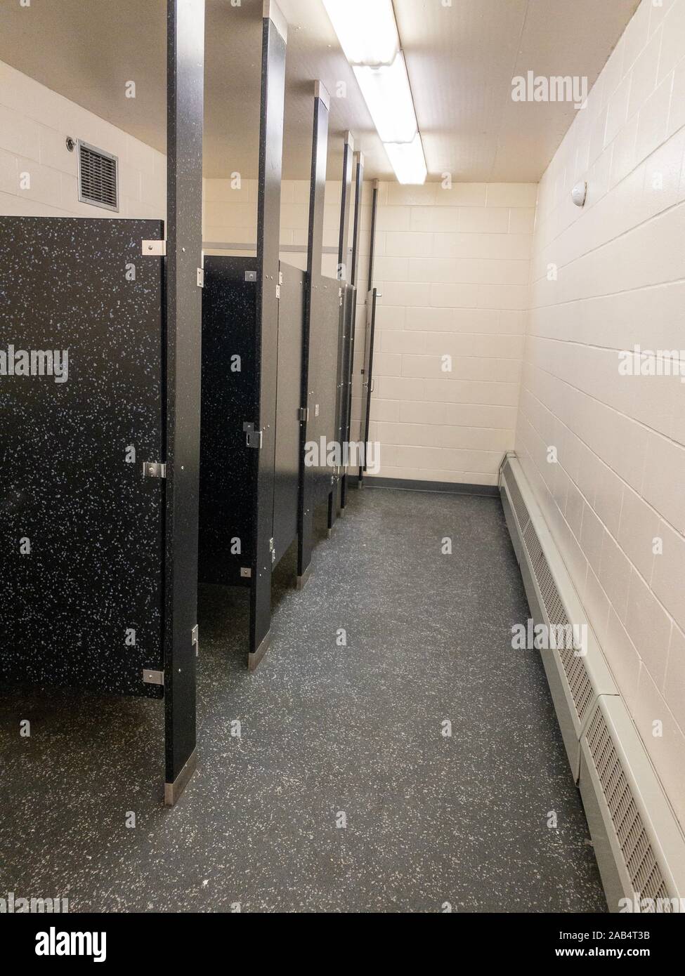 Inside a tiled public restroom with cubicle doors opening to the left ...