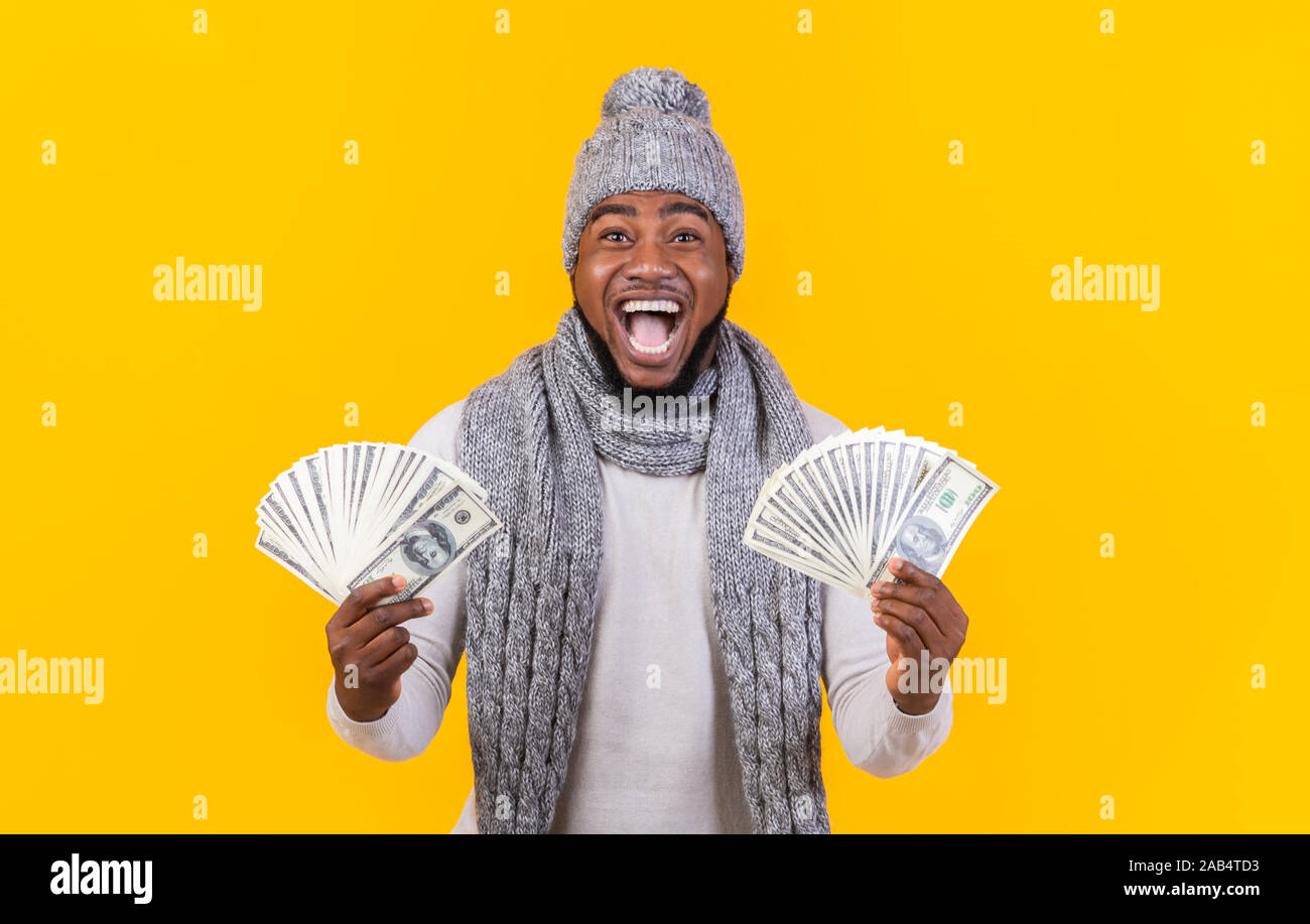Extremely happy young black man holding money in both hands Stock Photo ...