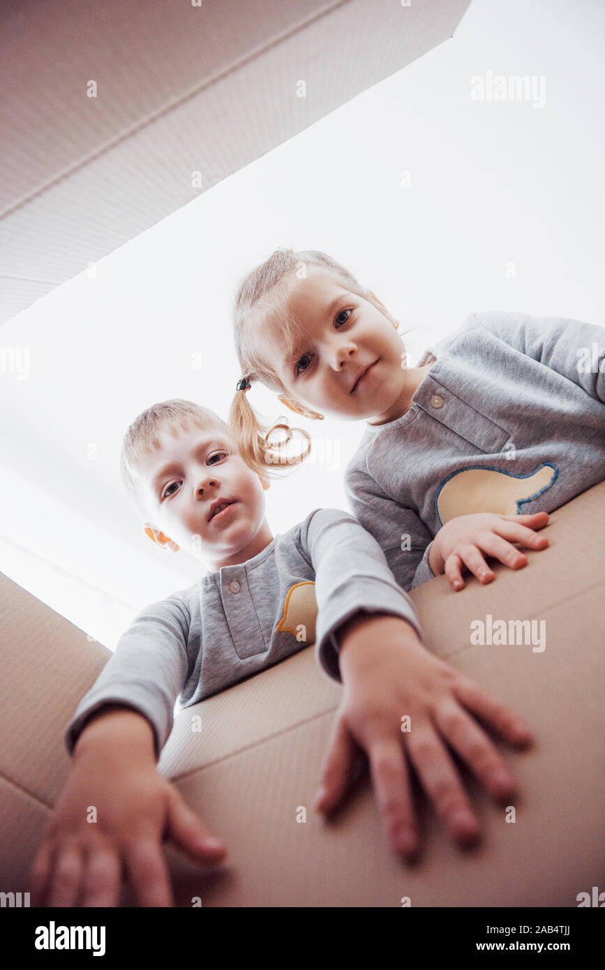Two a little kids boy and girl opening cardboard box and looking inside ...