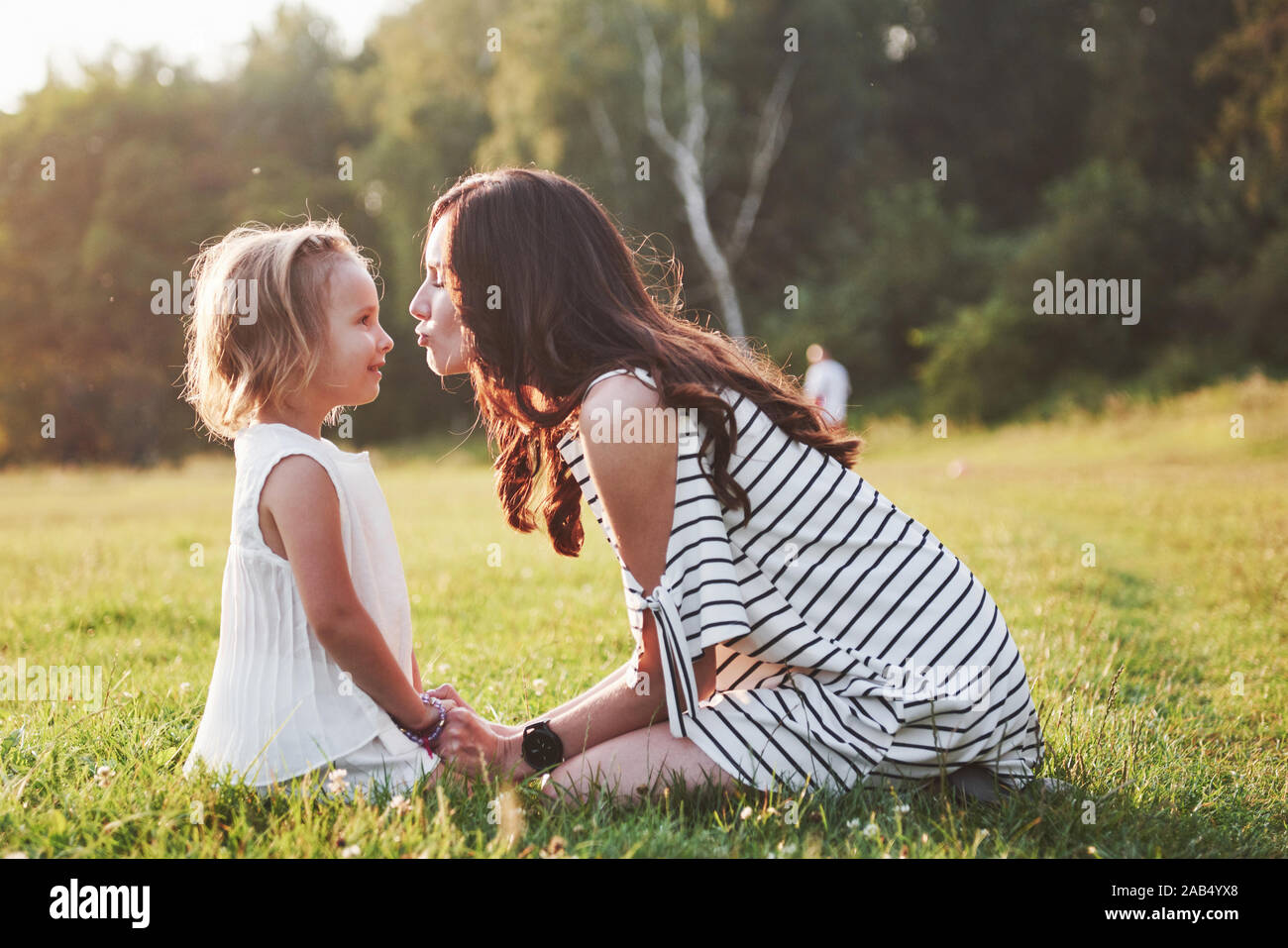 Happy mother and daughter hugging in a park in the sun on a bright summer background of herbs ...