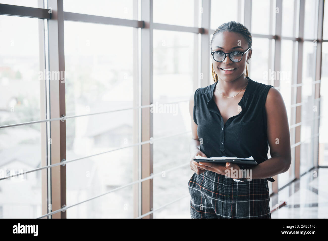 A thoughtful African American business woman wearing glasses holding ...