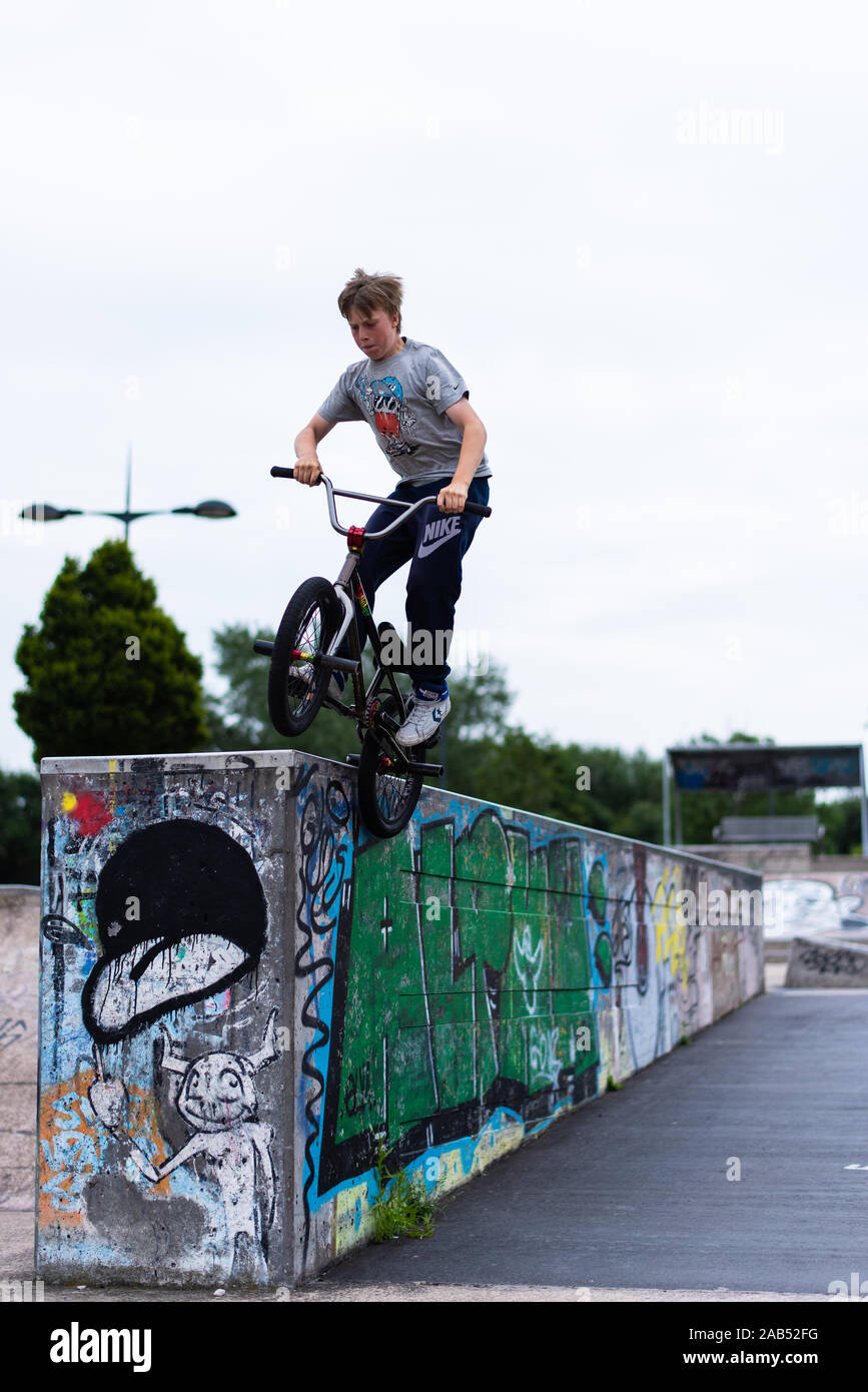 A young kid at the local skatepark practicing on his BMX, riding around ...