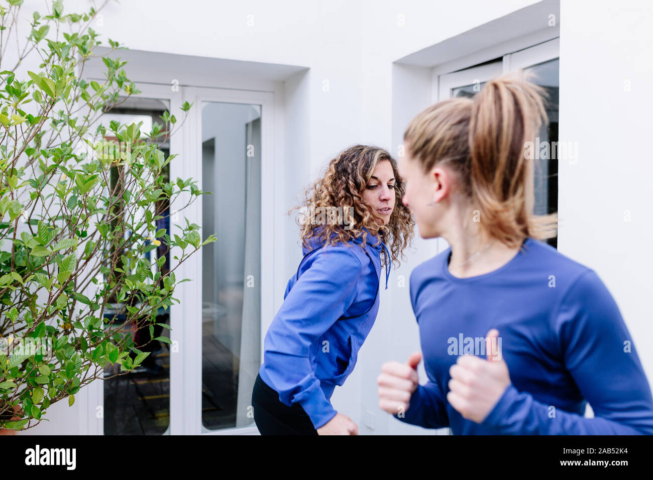 Two young women doing exercise together on a terrace Stock Photo - Alamy