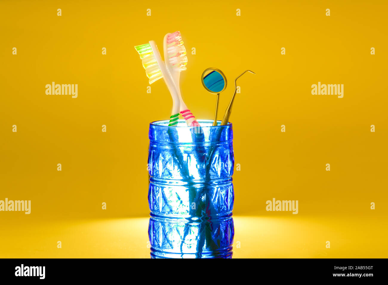 New plastic toothbrushes inside a glass, isolated on bright orange ...