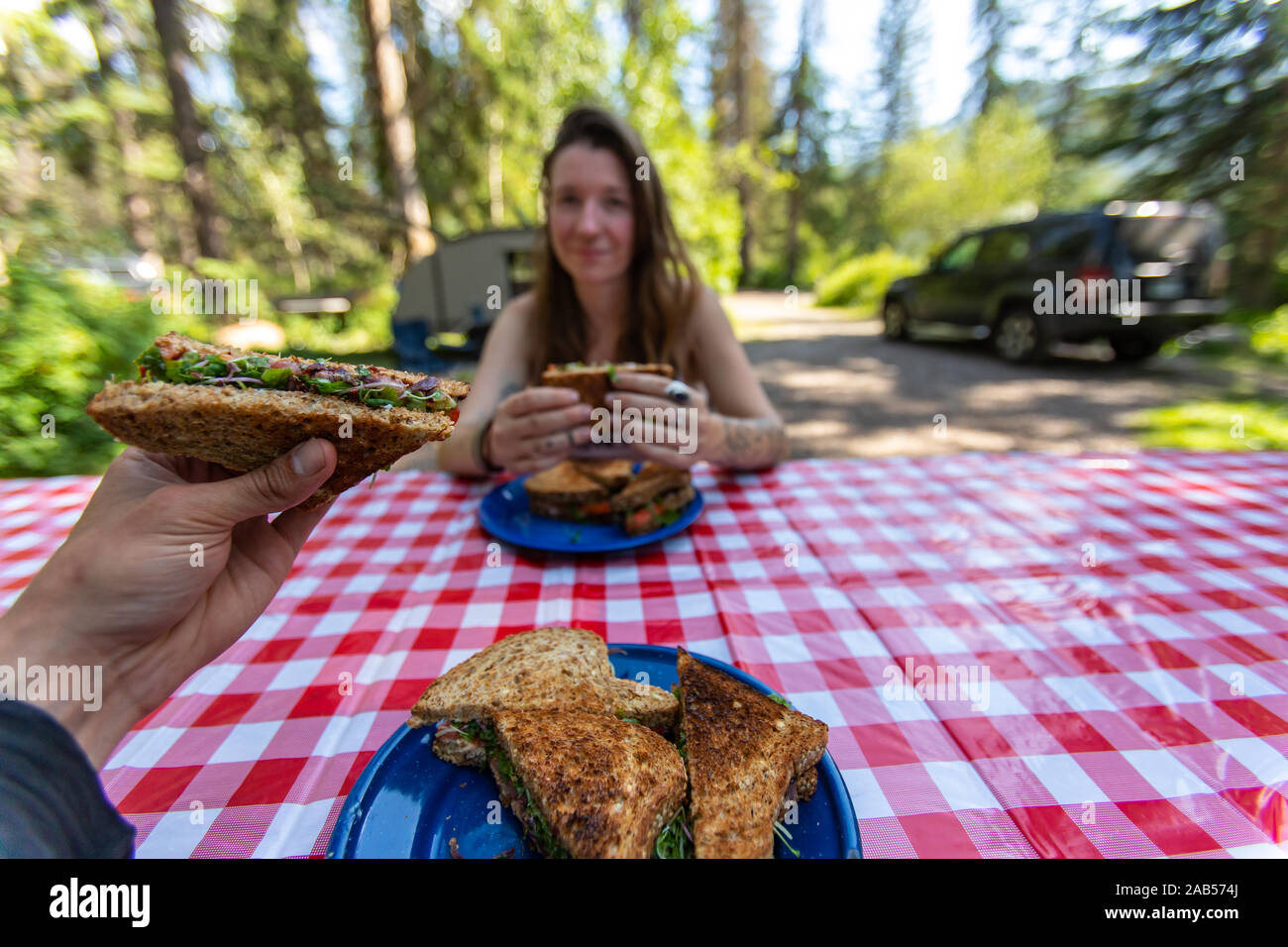 Selective focus of two adult persons sitting outside at a picnic table ...
