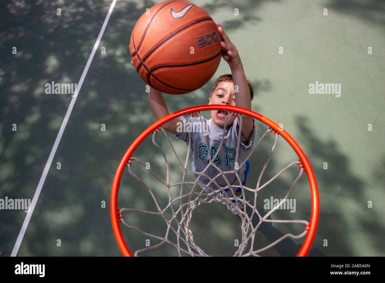 Boys dunking basketball at day camp Stock Photo - Alamy