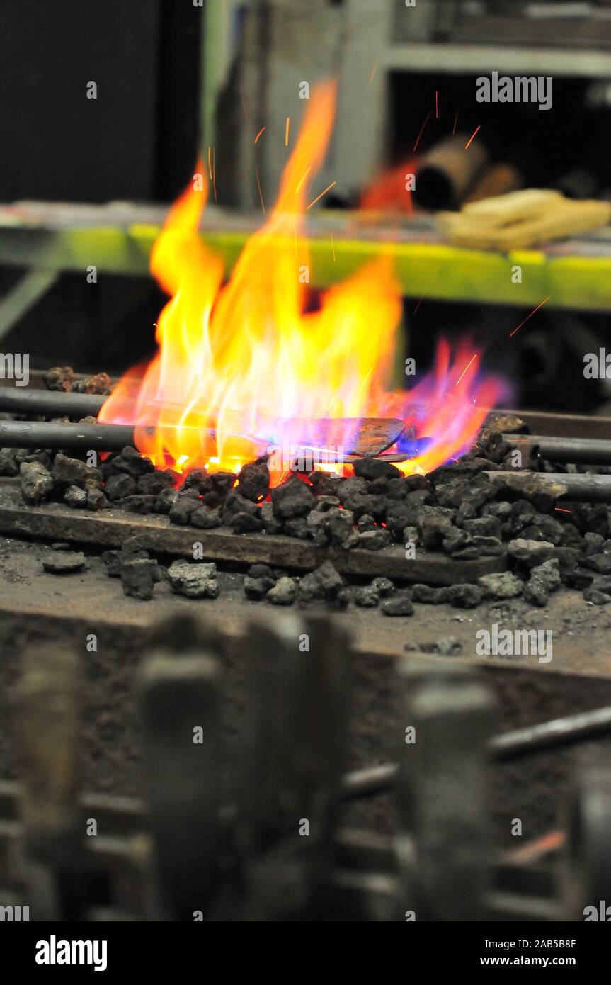 glowing iron in glowing coal in a forge while forging Stock Photo - Alamy