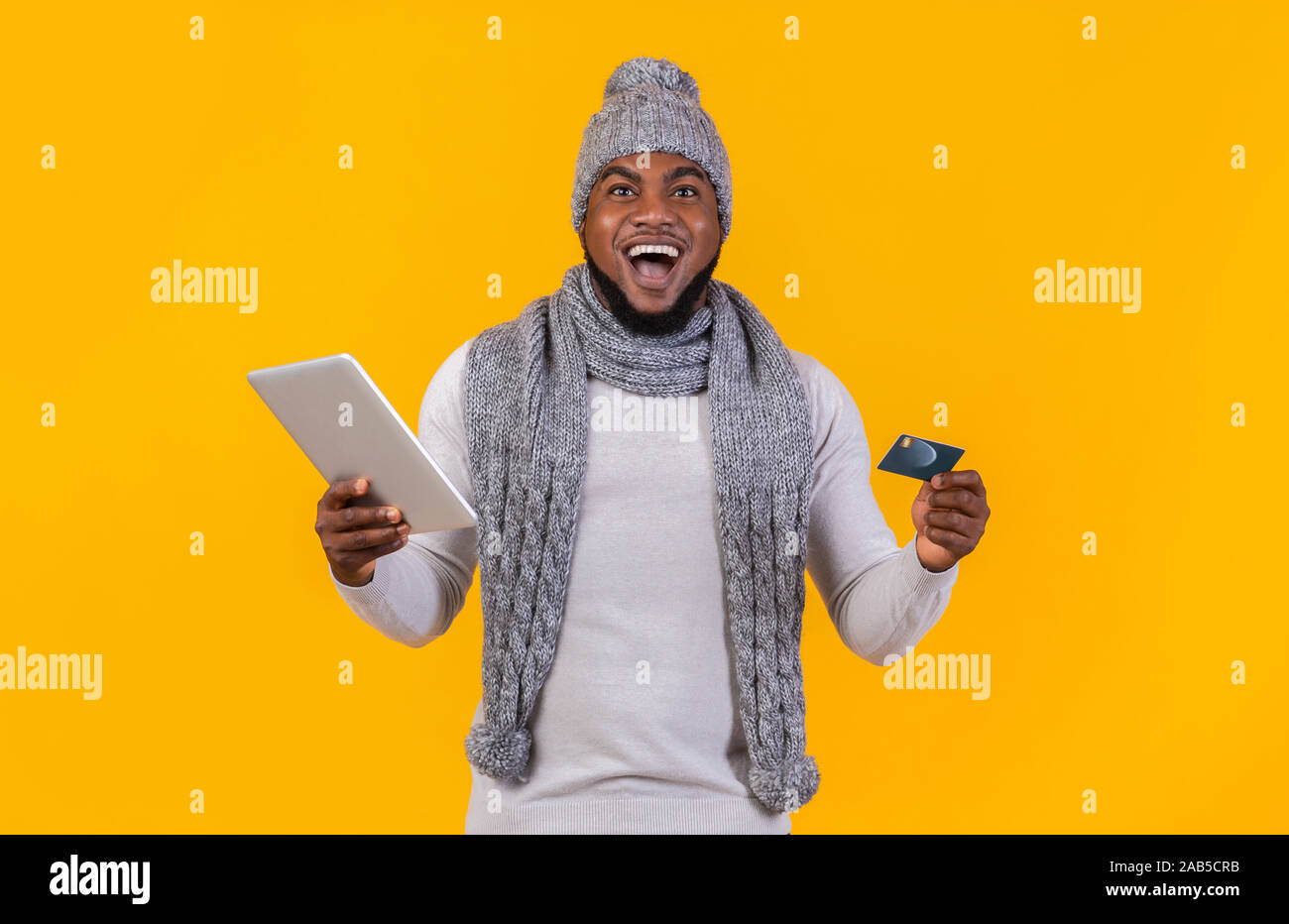 Excited afro guy holding digital tablet and credit card Stock Photo - Alamy