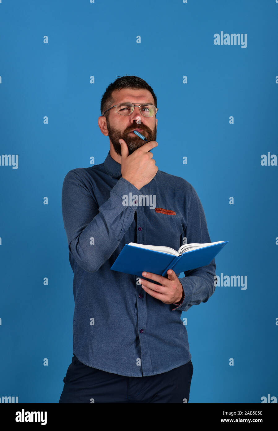 Professor with thinking face. Textbook in blue color in guys hands on ...