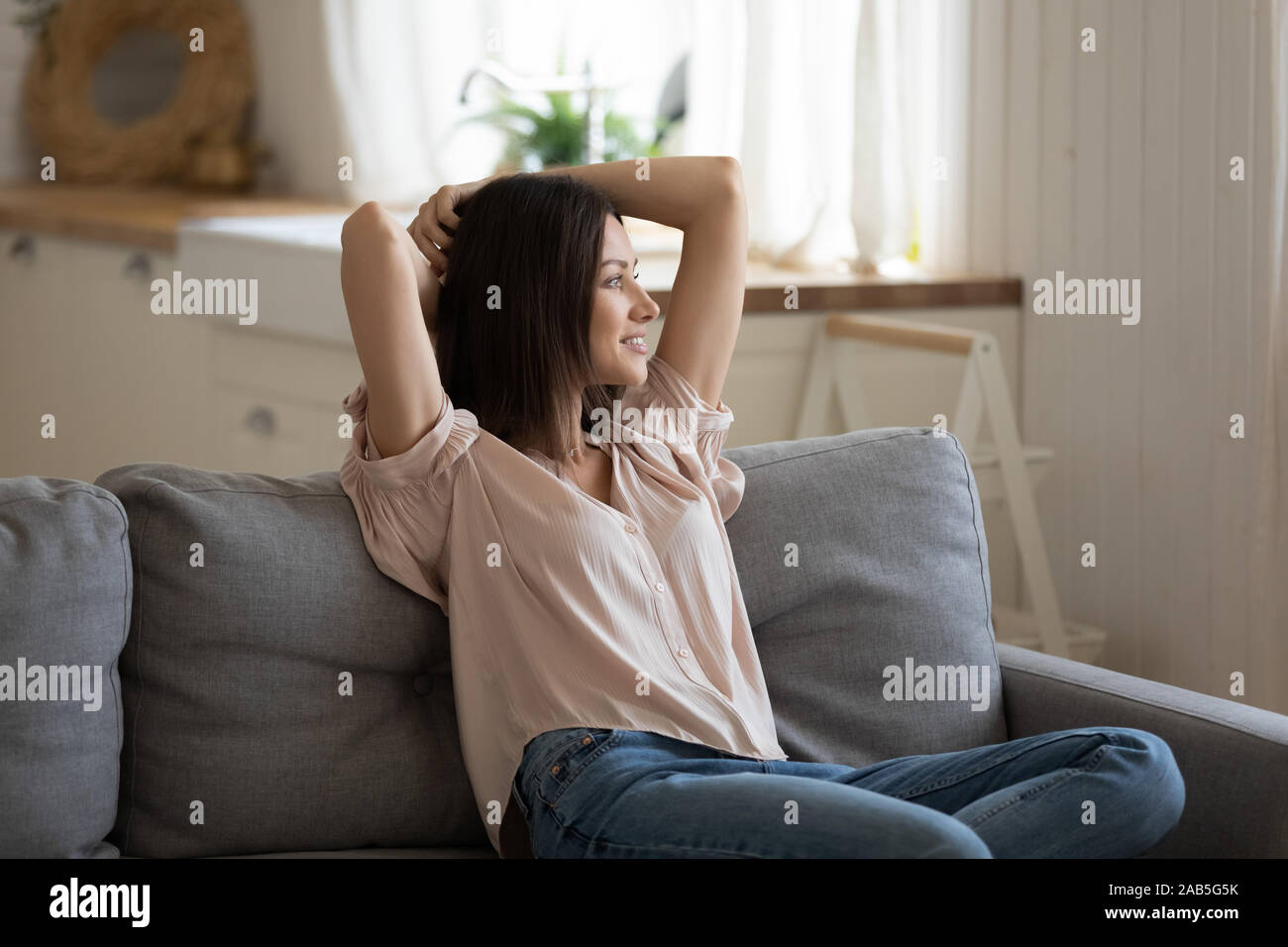 Relaxed lazy lady holding hands behind head lounge on sofa Stock Photo ...