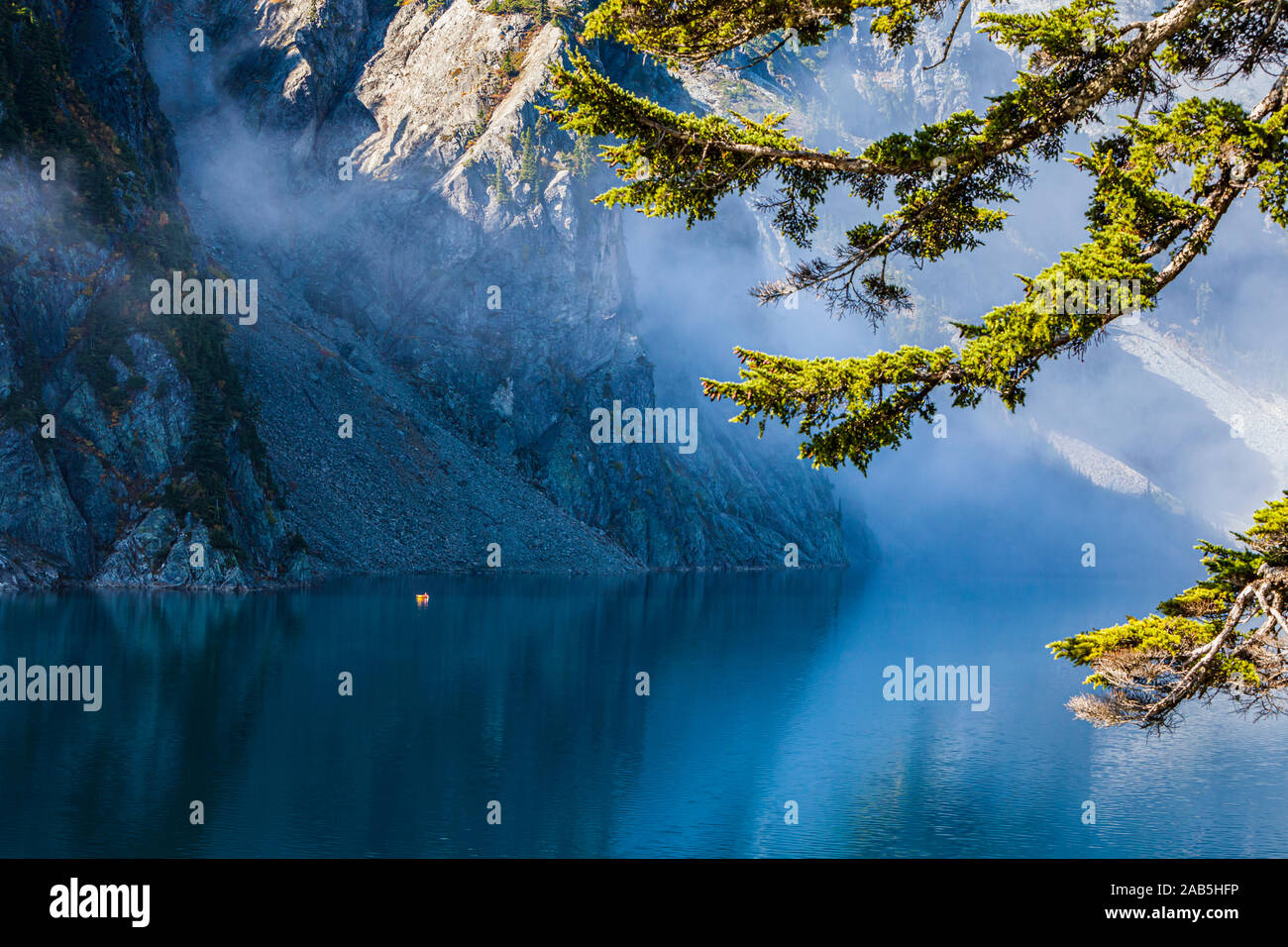 A man in a small inflatable raft rowing on Snow Lake above Snoqualmie ...