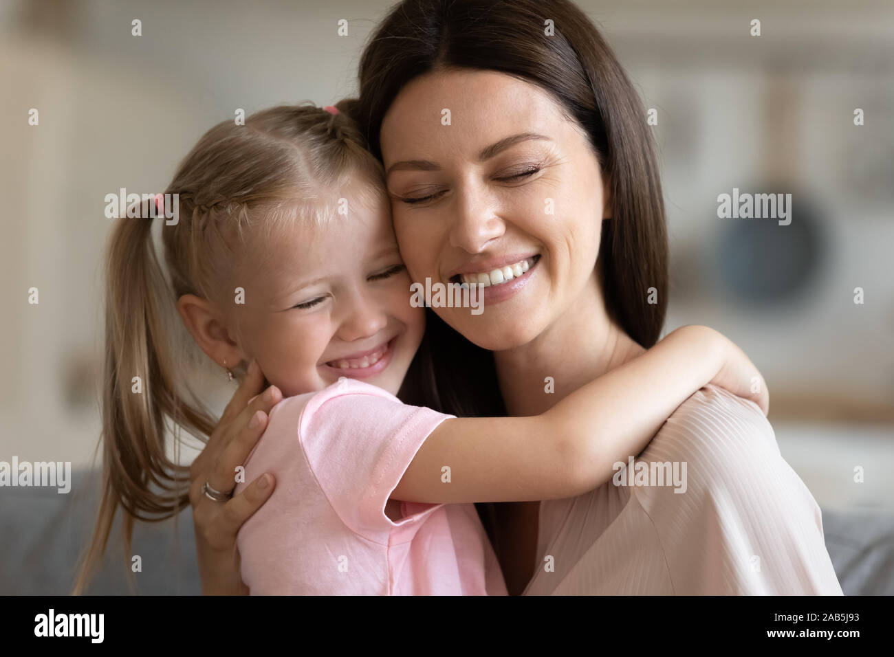 Caring smiling foster mother embrace cute adopted daughter at home ...