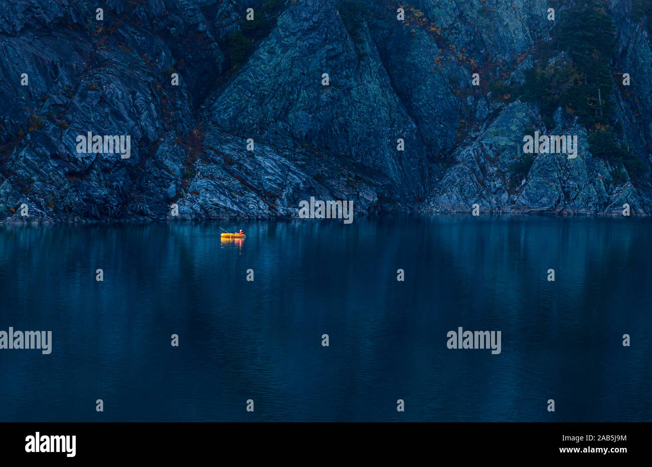 A man in a small inflatable raft rowing on Snow Lake above Snoqualmie ...