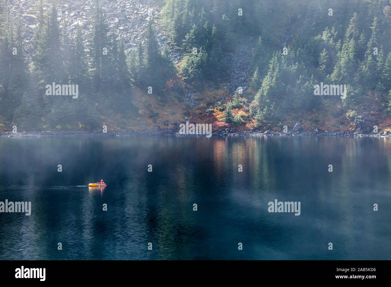 A man in a small inflatable raft rowing on Snow Lake above Snoqualmie ...