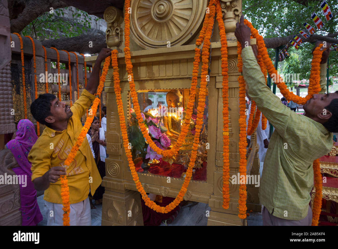 Temple workers decorate a Buddha statue and the walls surrounding the ...