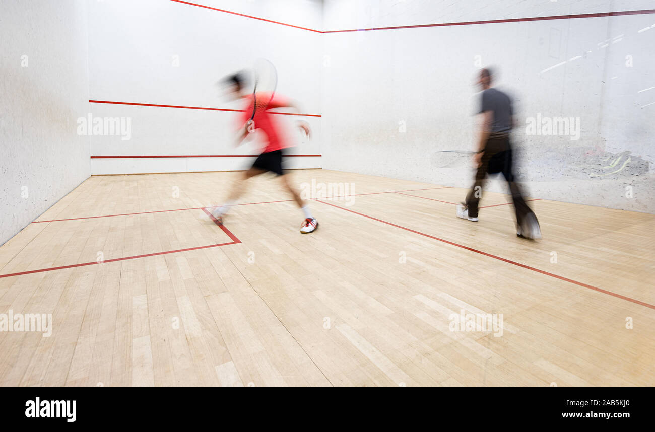Squash players in action on a squash court (motion blurred image; color ...