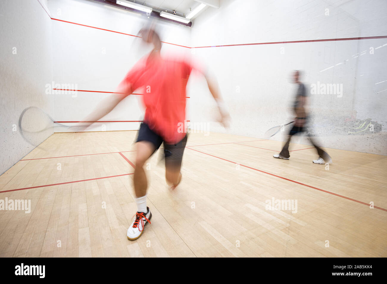 Squash players in action on a squash court (motion blurred image; color ...