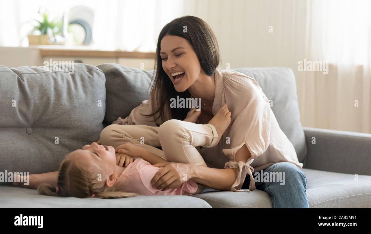 Cheerful mother tickling cute child daughter laughing playing on sofa Stock Photo - Alamy