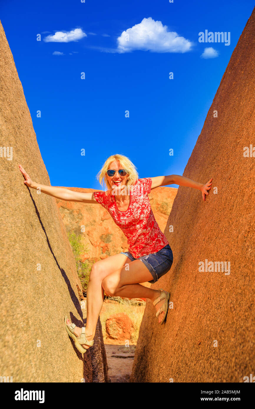 Happy woman wedged balancing between two naturally split boulder in ...