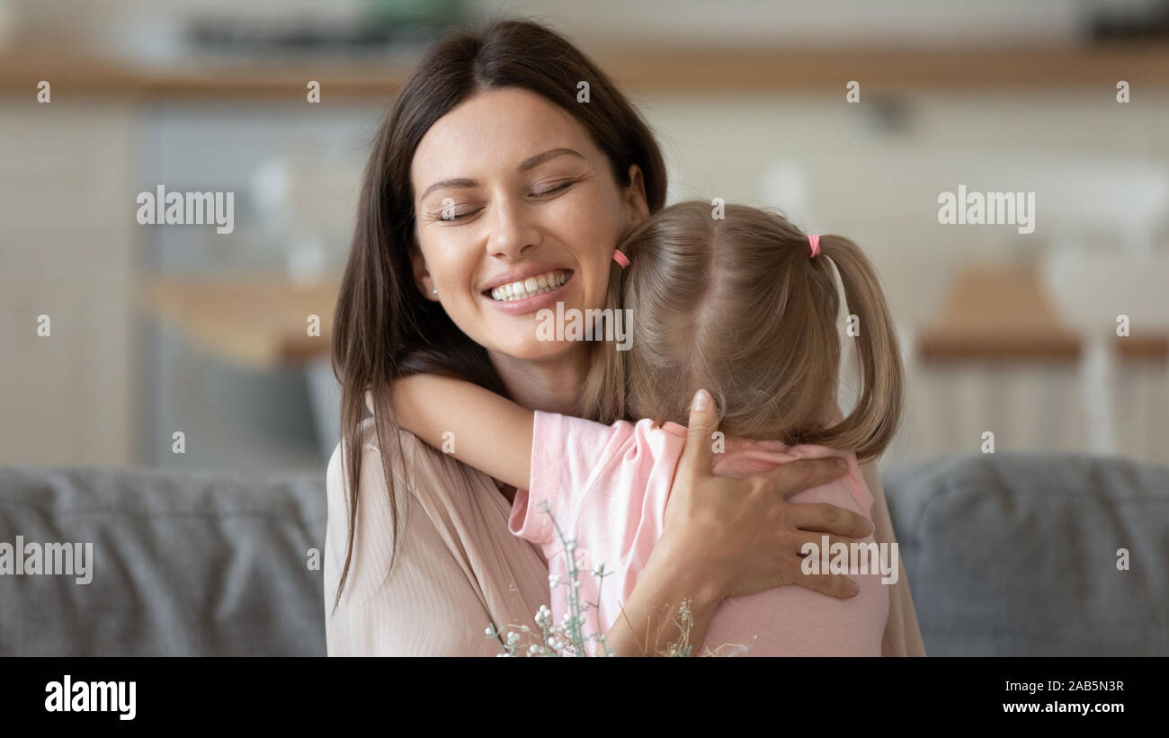 Caring happy mother embracing child daughter feeling tenderness at home ...
