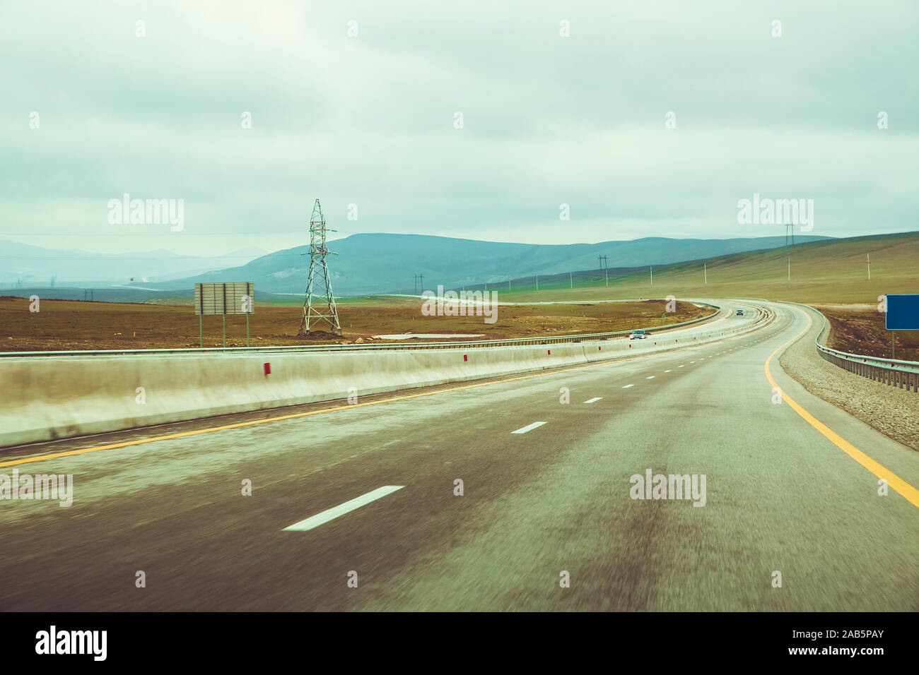 road receding into the distance in open countryside under a cloudy ...
