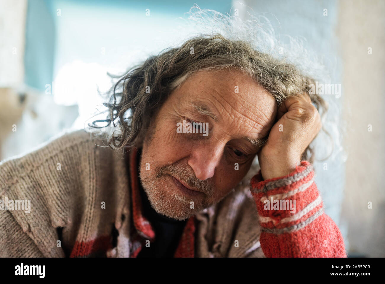 Portrait of a senior man in torn sweater with worried and tired ...