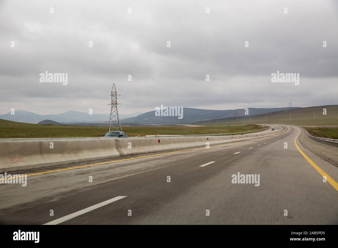 road receding into the distance in open countryside under a cloudy ...