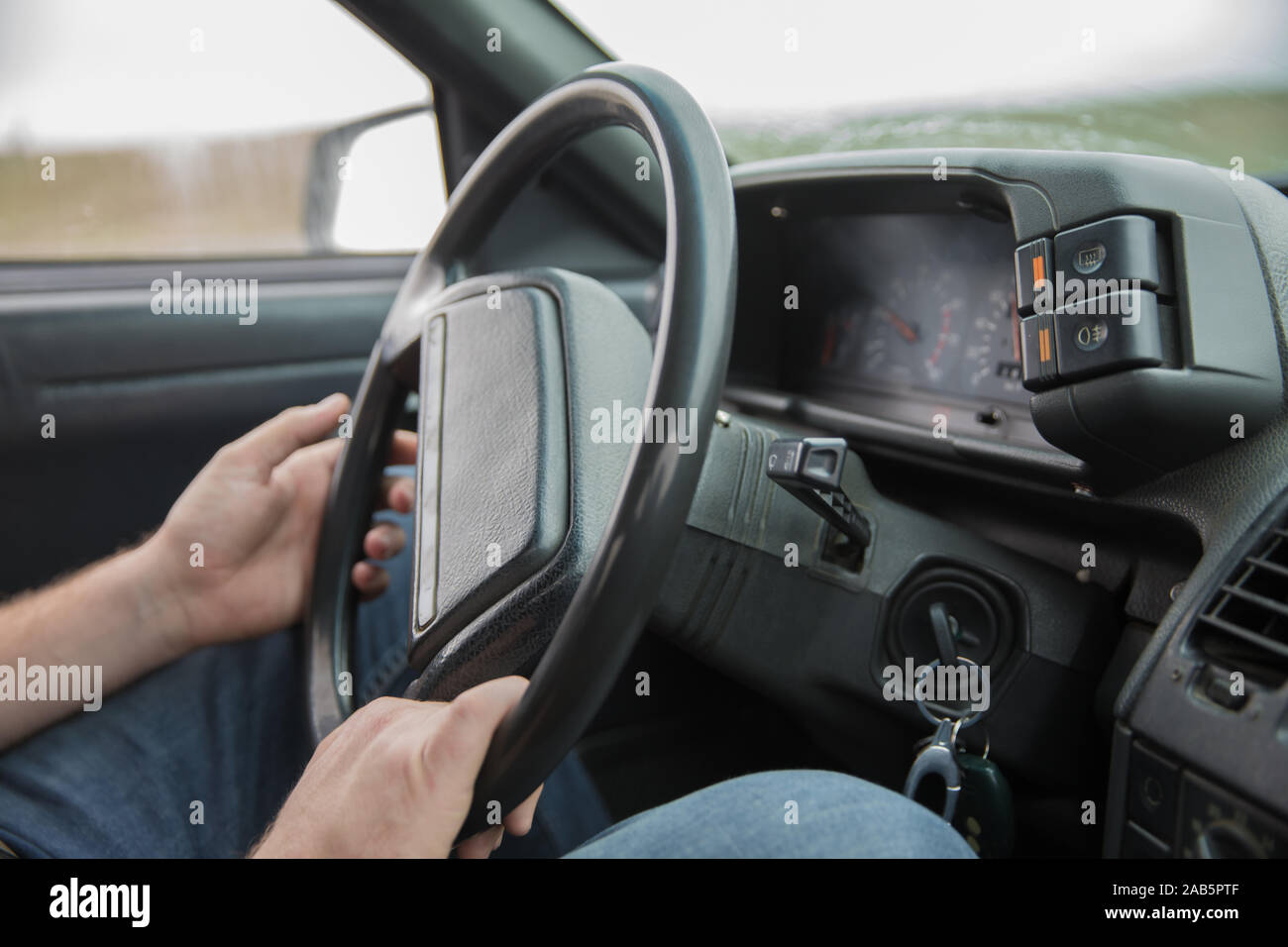 Car Interior. Male arms holding leathern rudder of car .the man grabs ...