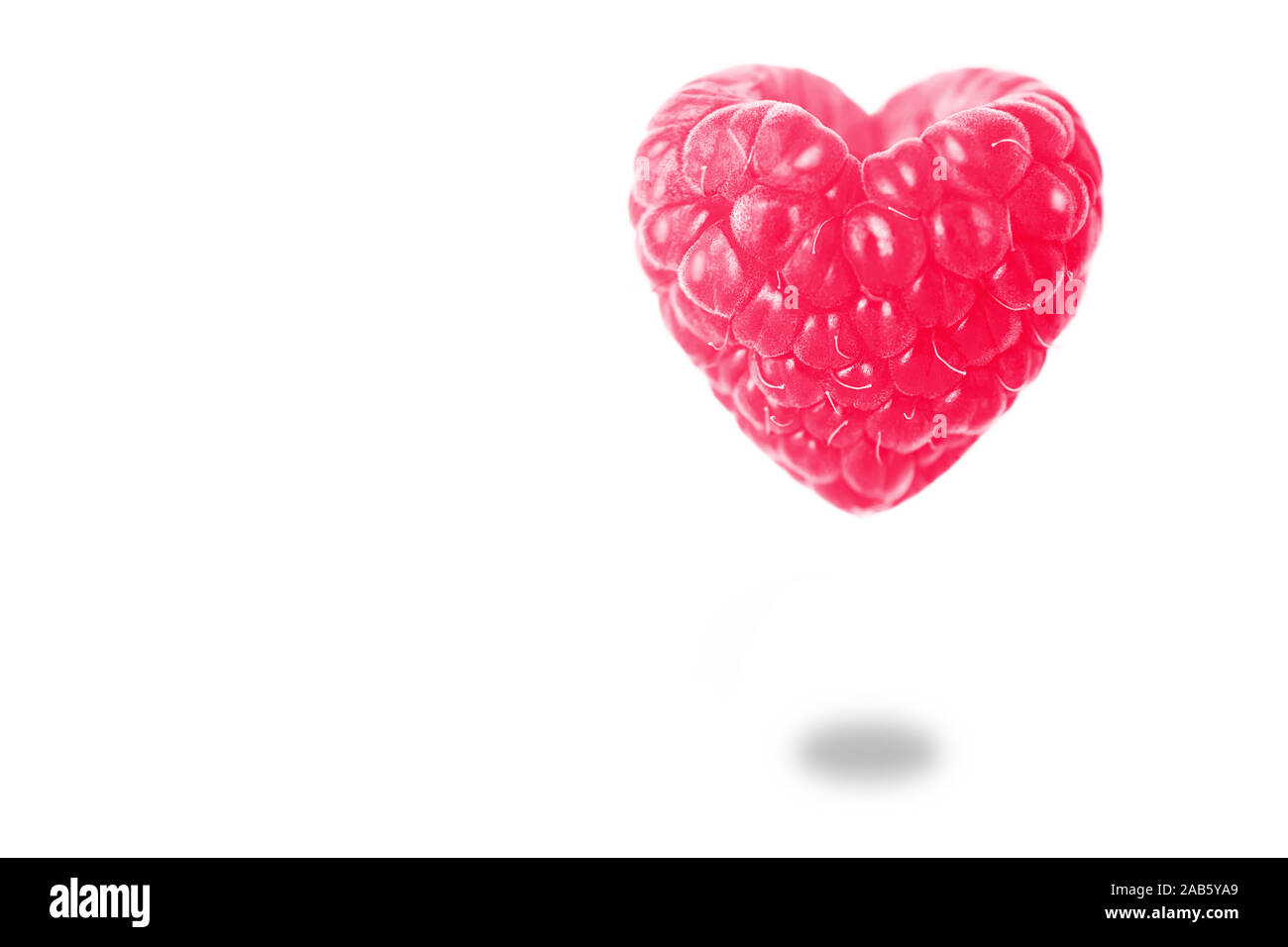 Raspberry in the shape of a heart with a shadow on a white background ...