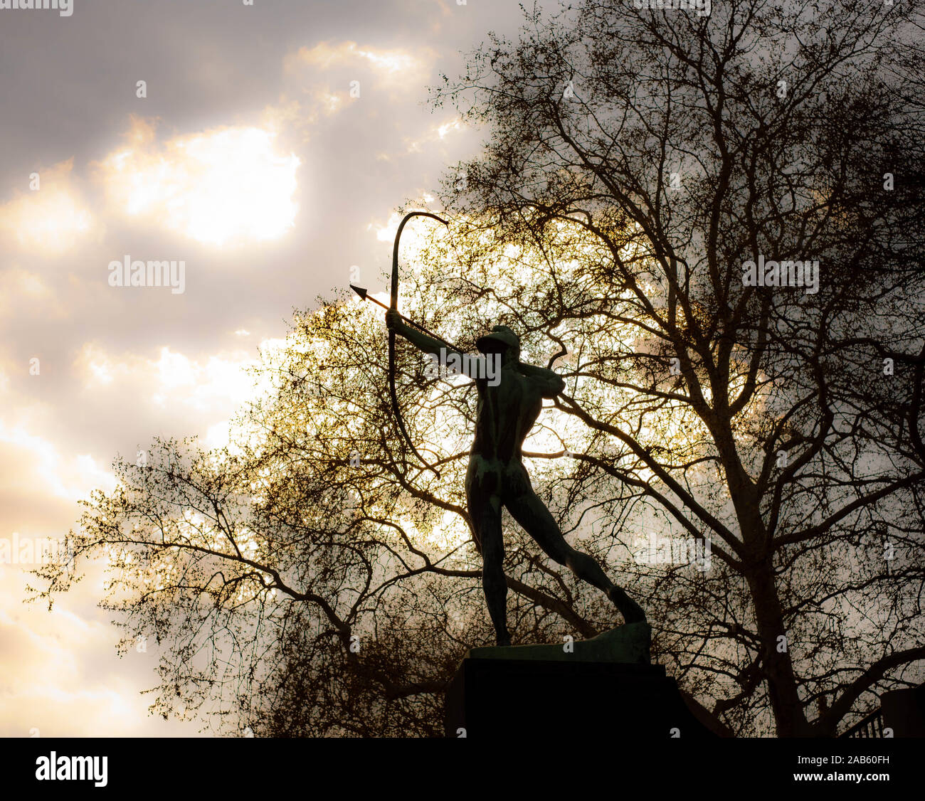 Silhouette of the archer figure from low angle and high trees in park ...