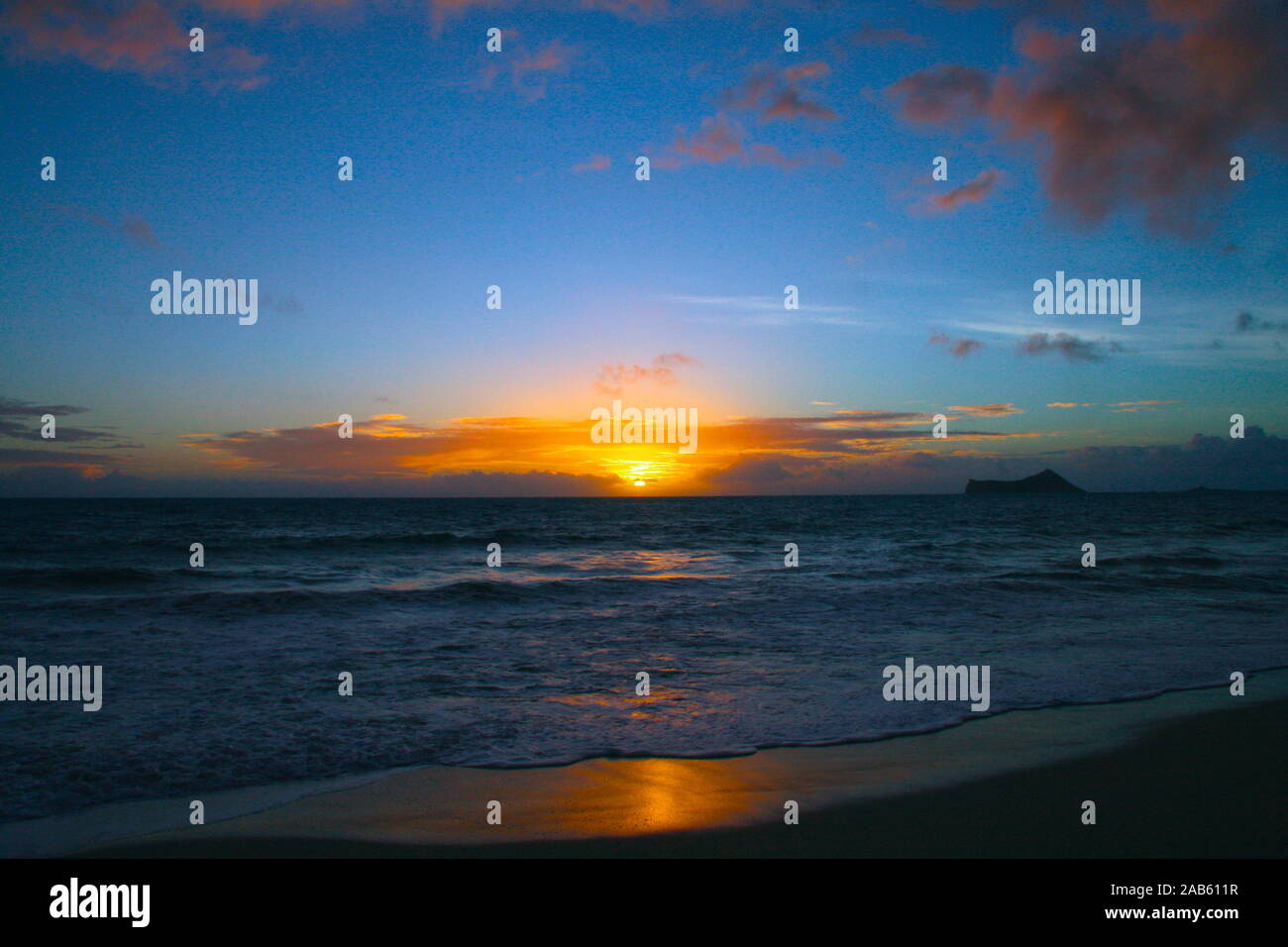 Rising sun on the horizon above a calm ocean or sea. On the blue sky ...