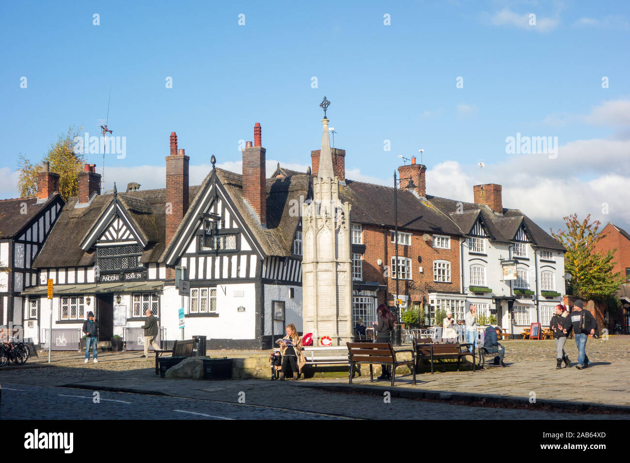 People sitting in the ancient cobbled market square in the Cheshire ...