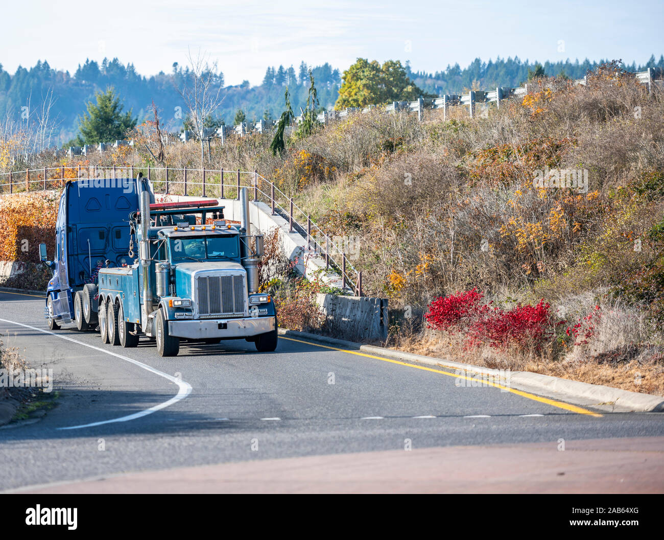 Mobile big rig tow truck with lifting boom and three driving truck rear ...
