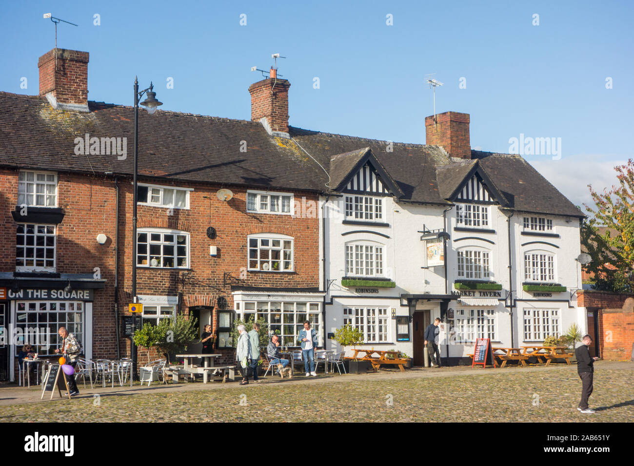 People sitting in the ancient cobbled market square in the Cheshire ...