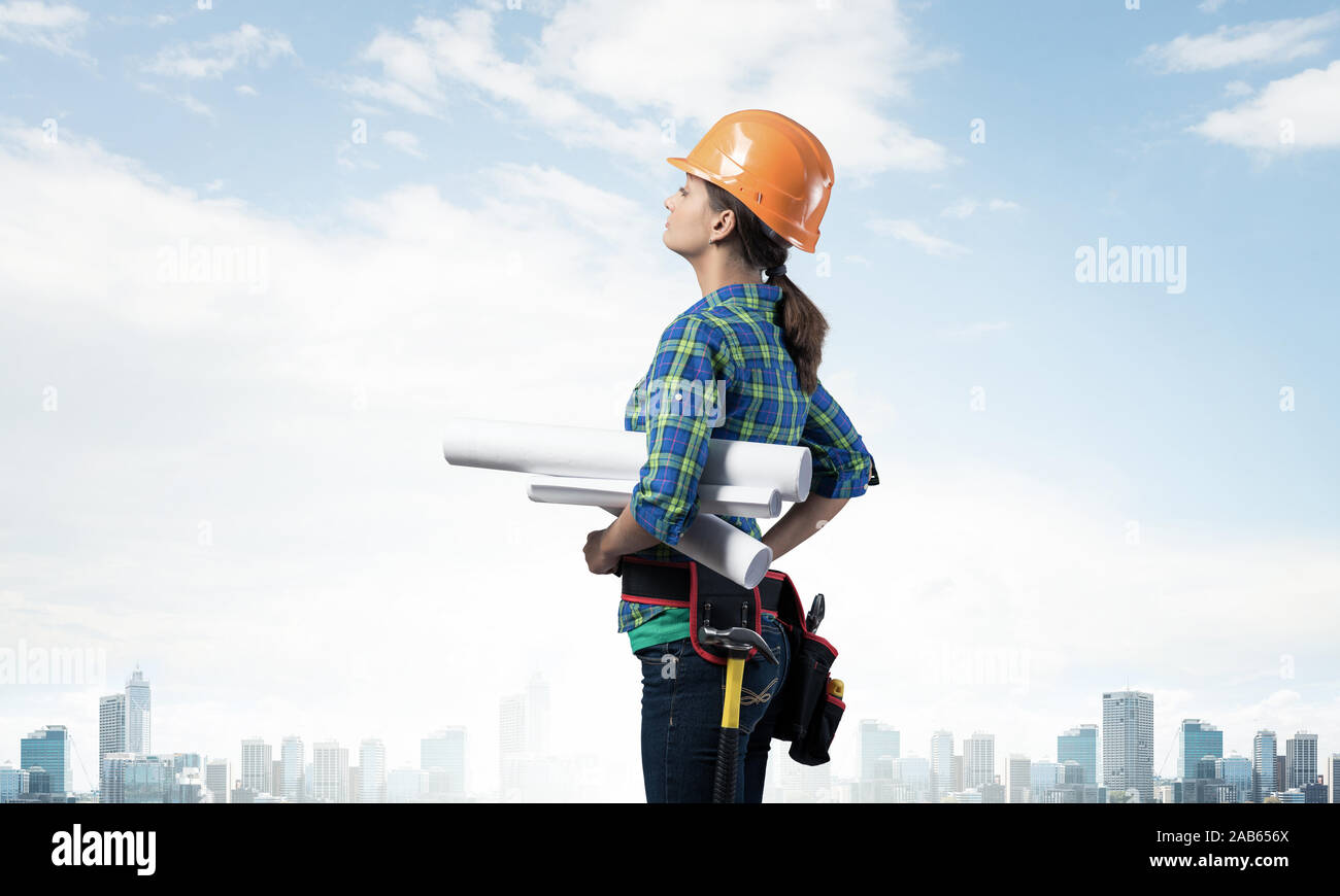 Female engineer in hardhat standing with blueprint Stock Photo - Alamy