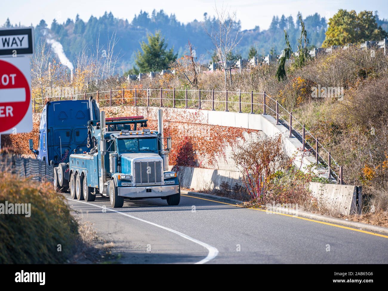 Mobile big rig tow truck with lifting boom and three driving truck rear ...