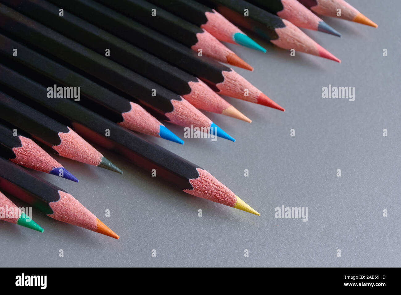 Close-up of an row of black colored pencils against a grey metallic ...