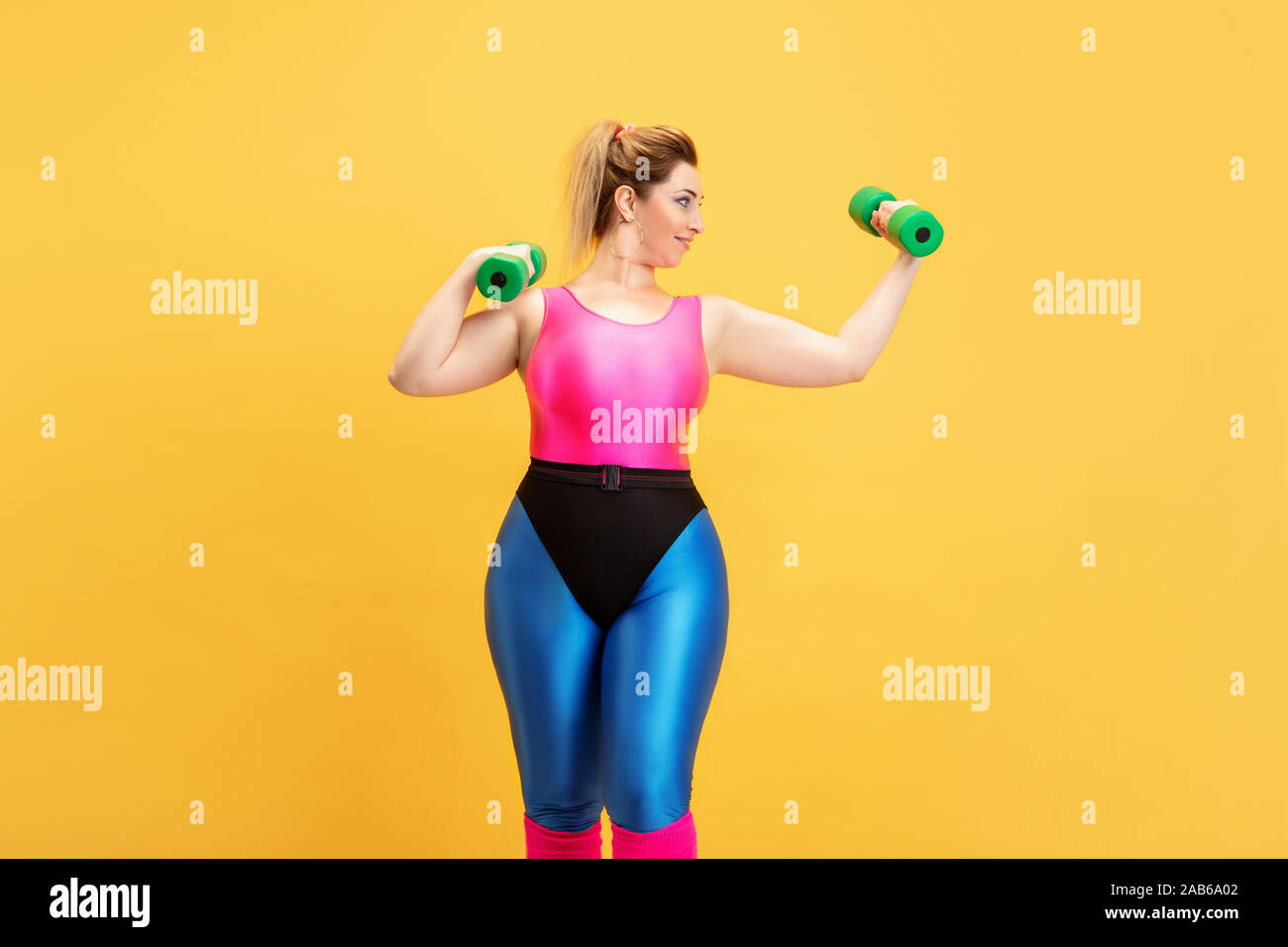 Young caucasian plus size female model's training on yellow background ...