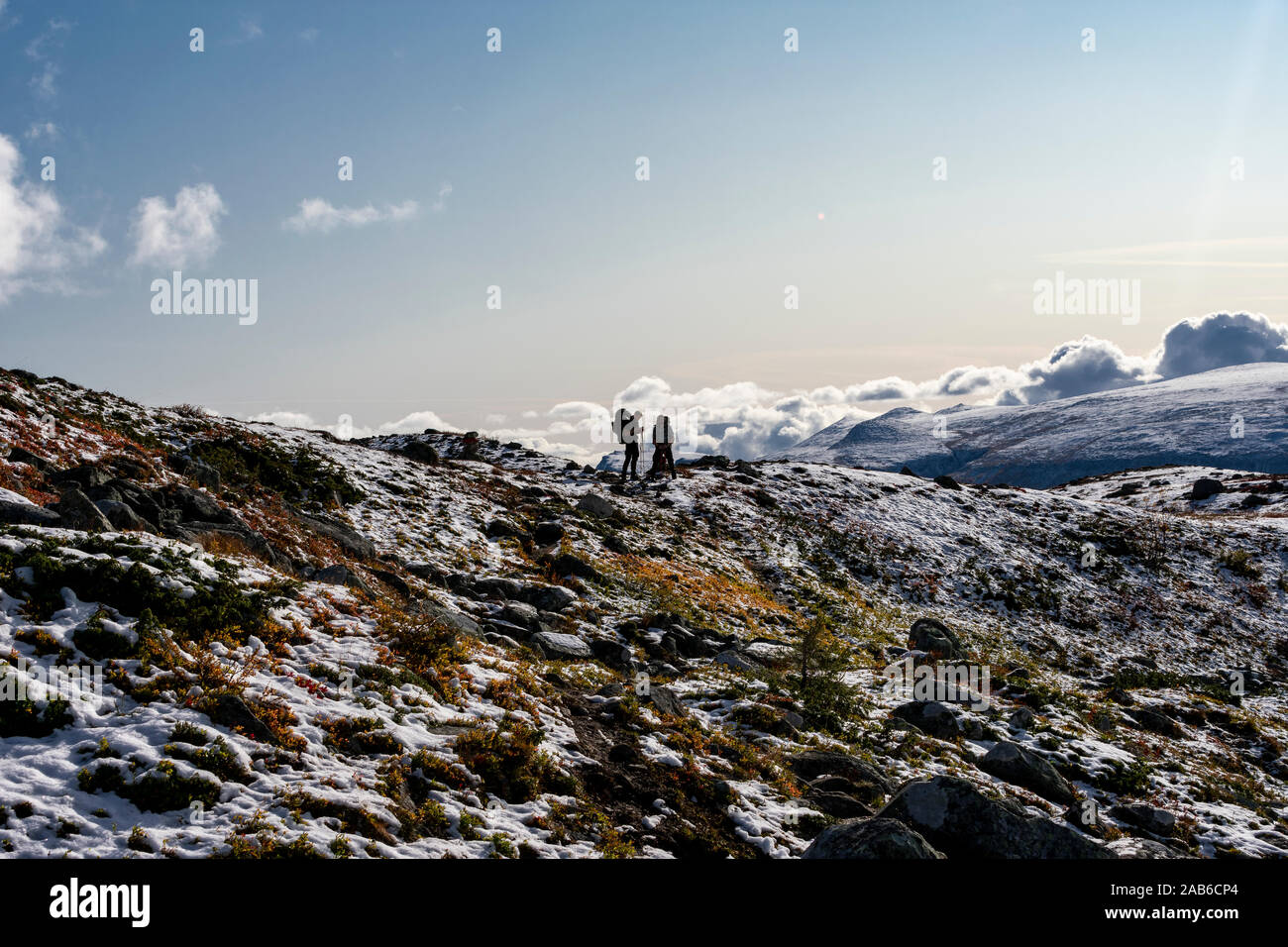 Two hikers standing on the snowy tundra during a beautiful sunny day in ...