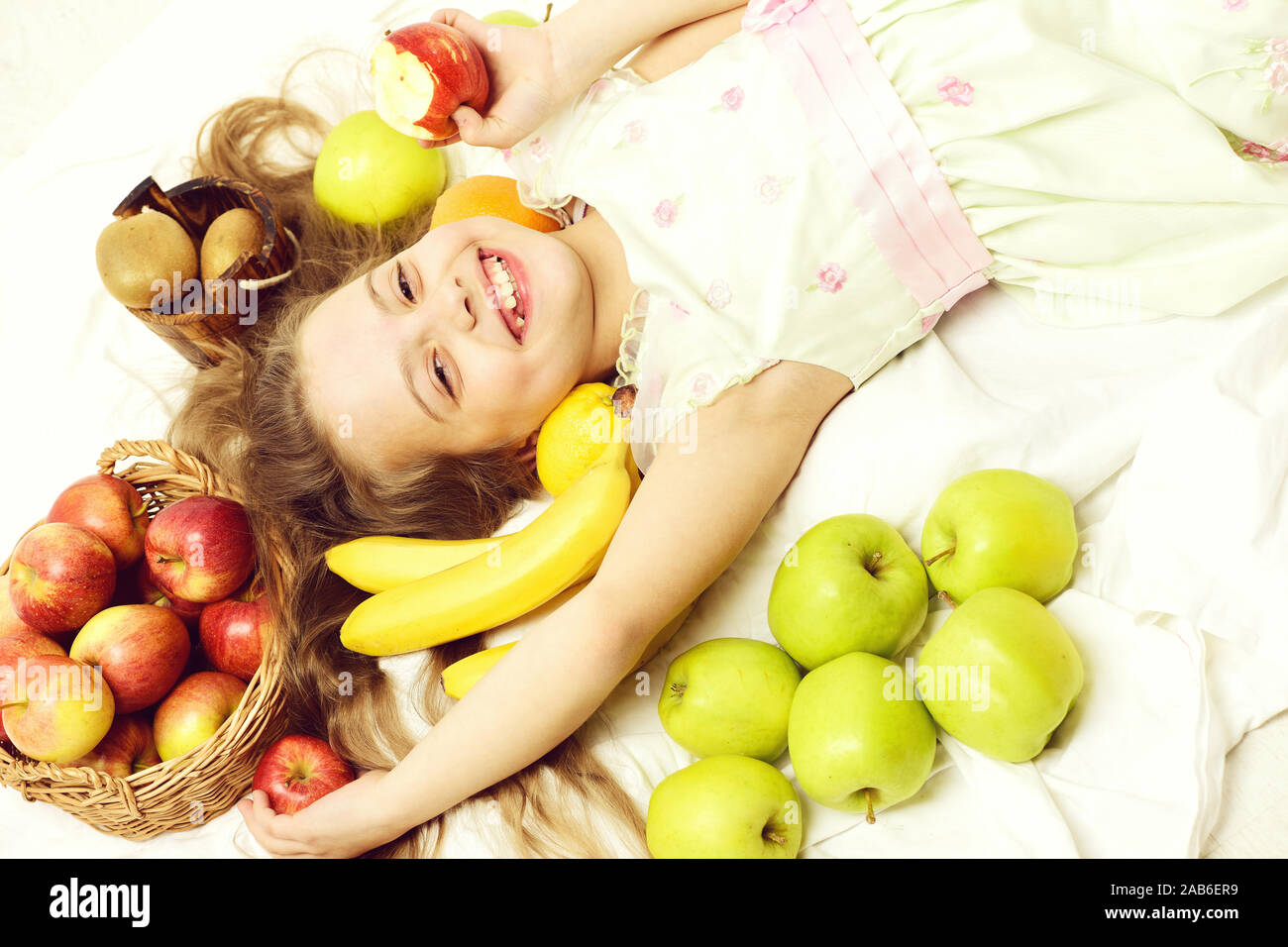 fruit and girl. cute baby girl laying with colorful fruits in basket ...