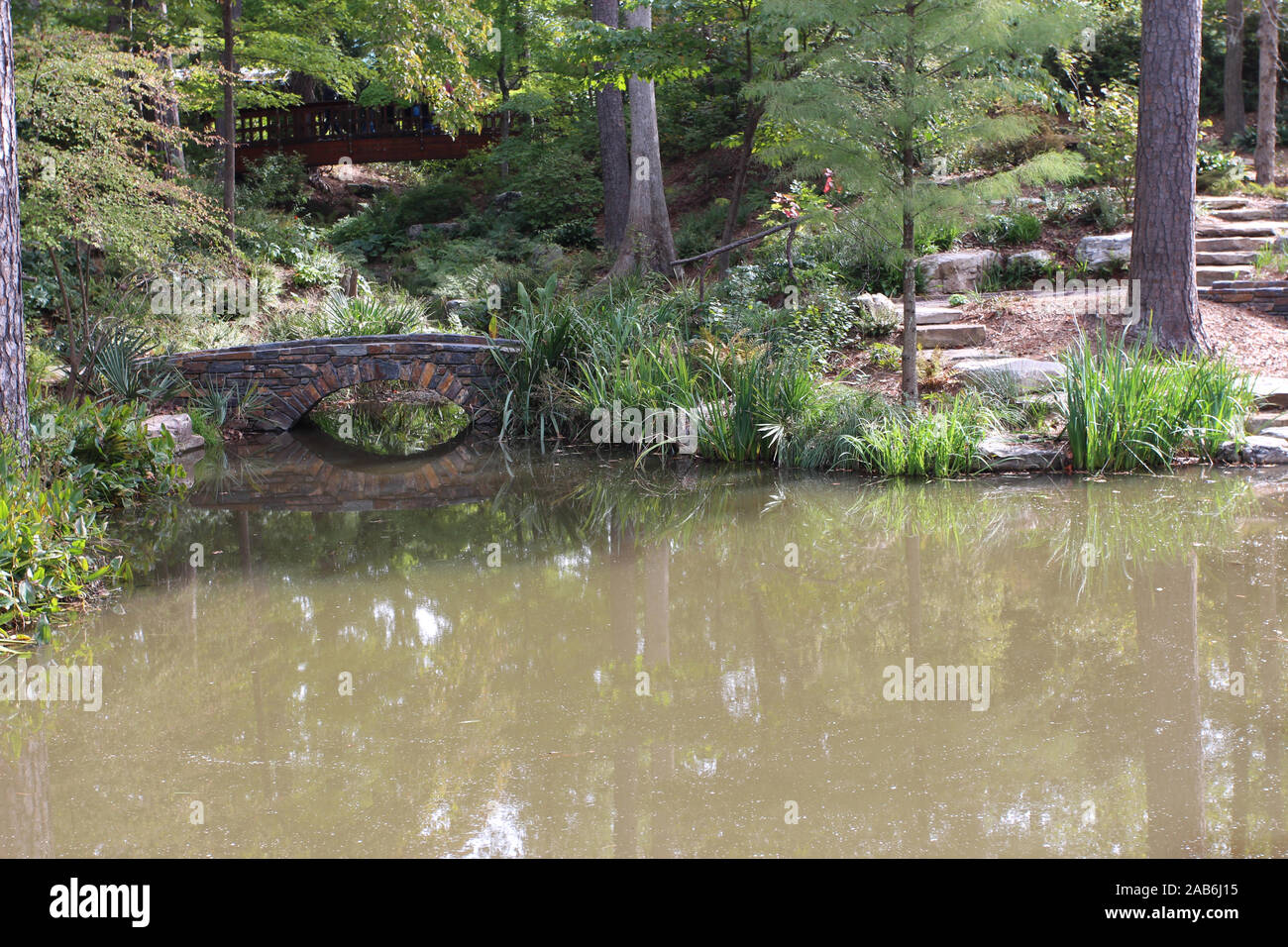 Landscaped paths and bridges through a forest and around a pond in ...