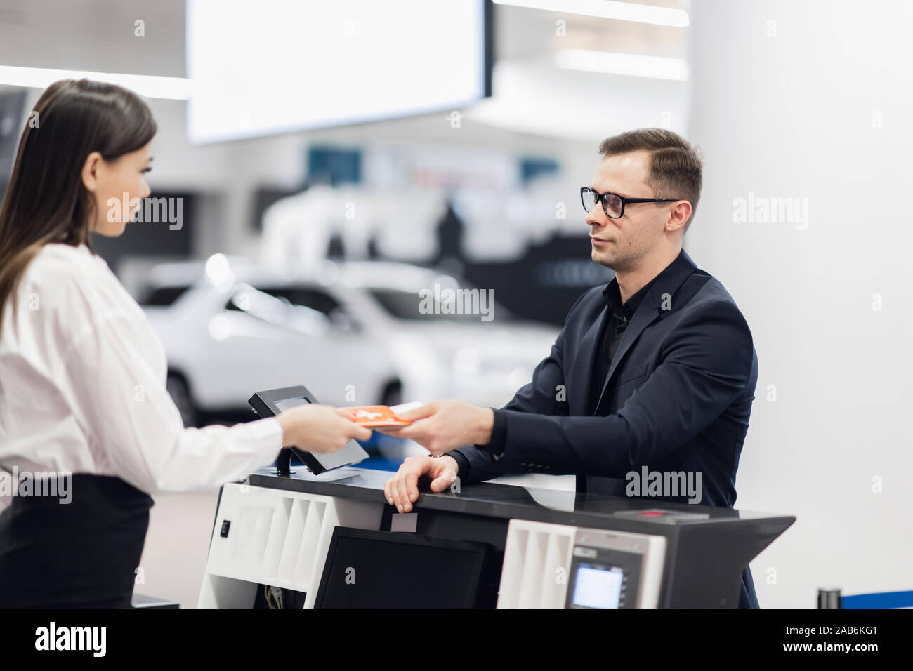 Side view of handsome man wearing glasses giving passport to staff at ...