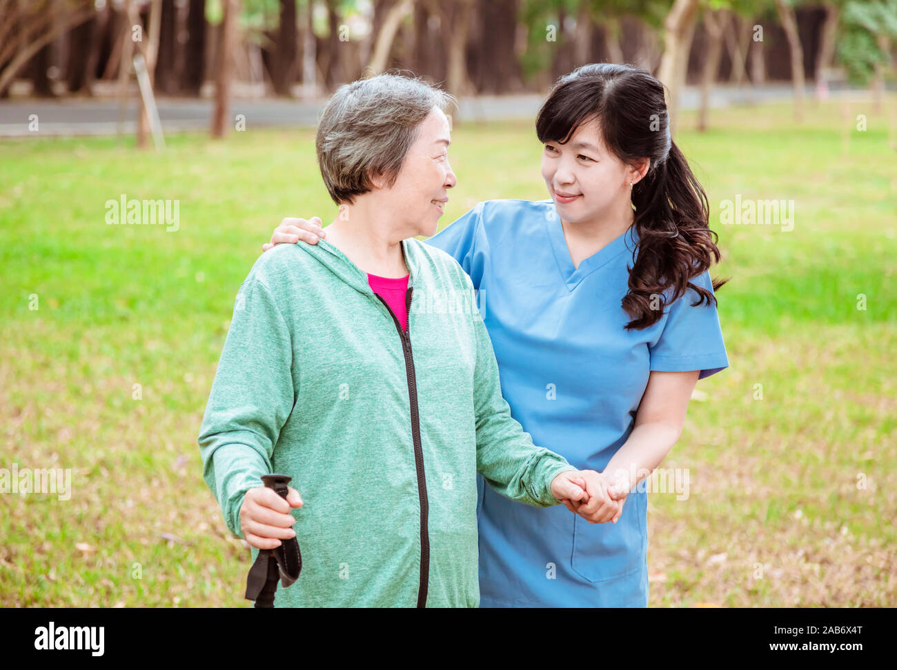 Smiling nurse helping senior woman to walk around the park Stock Photo ...
